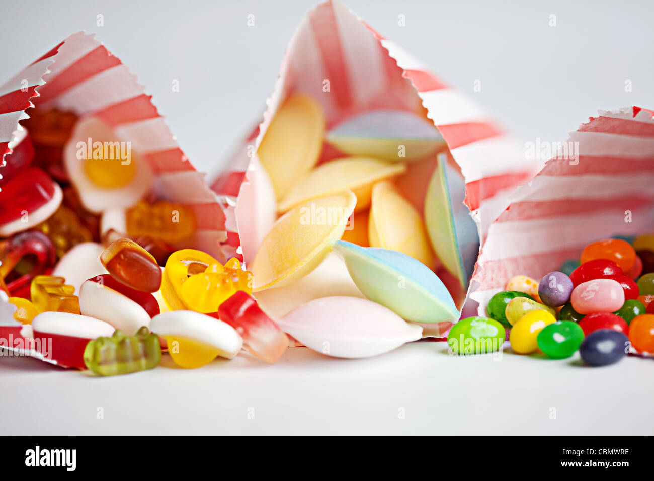 Three red and white striped sweetie bags, each overfloweing with ...