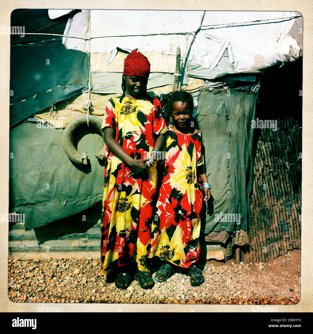 Teenage girl And Child Sister Same Colorful Dress Outside Slum Hut In ...