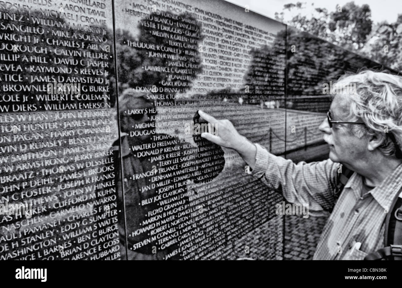 Old soldier looking at friends name at reflections of hero names of war ...