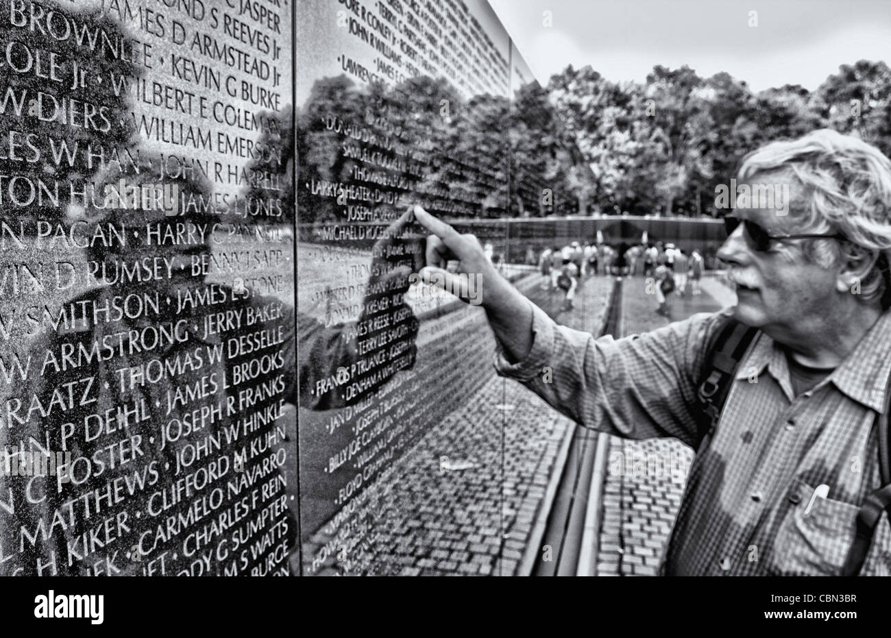Old soldier looking at friends name at reflections of hero names of war ...