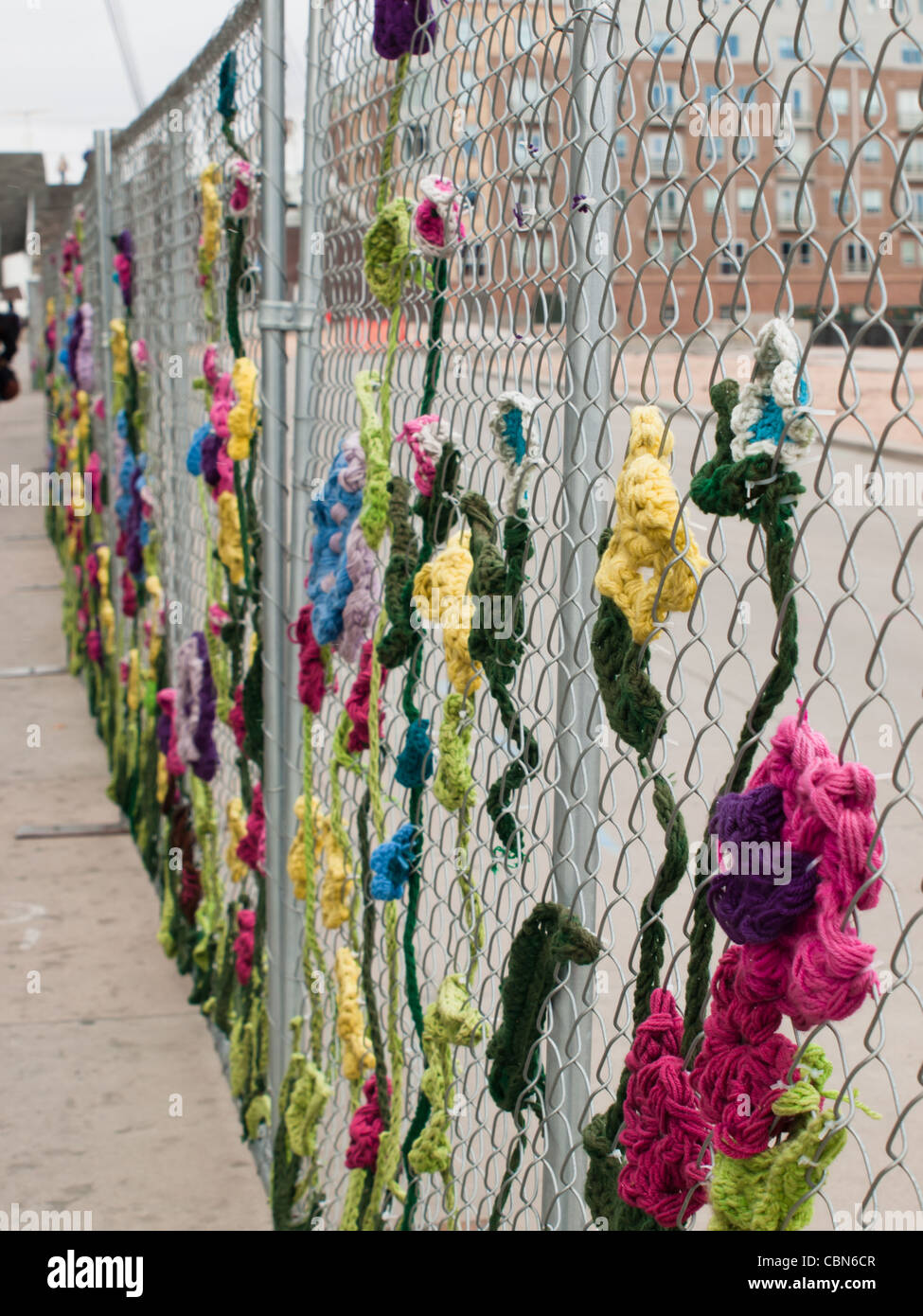 Construction fence covered with crocheted garden creatures like bugs ...