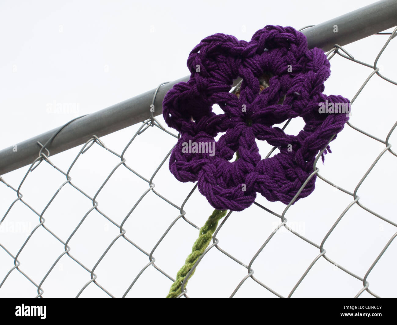 Construction fence covered with crocheted garden creatures like bugs ...