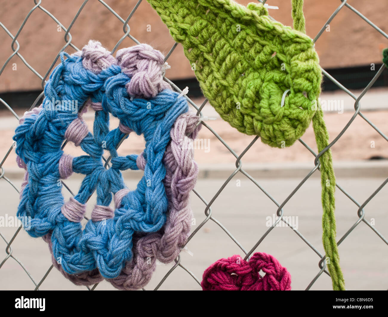 Construction fence covered with crocheted garden creatures like bugs ...
