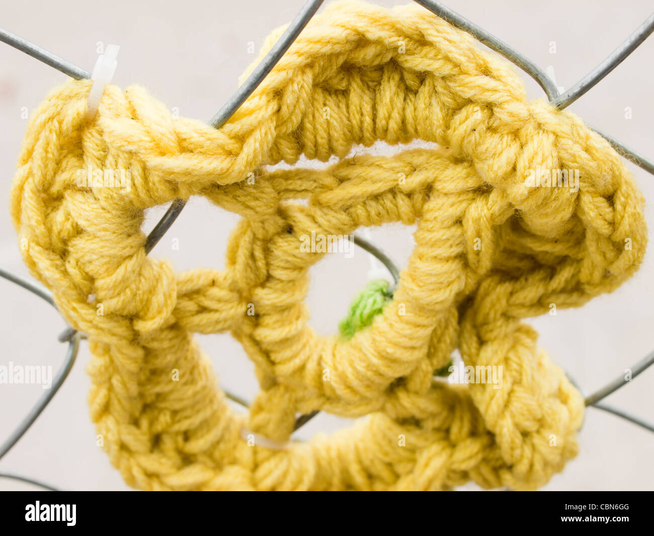 Construction fence covered with crocheted garden creatures like bugs ...