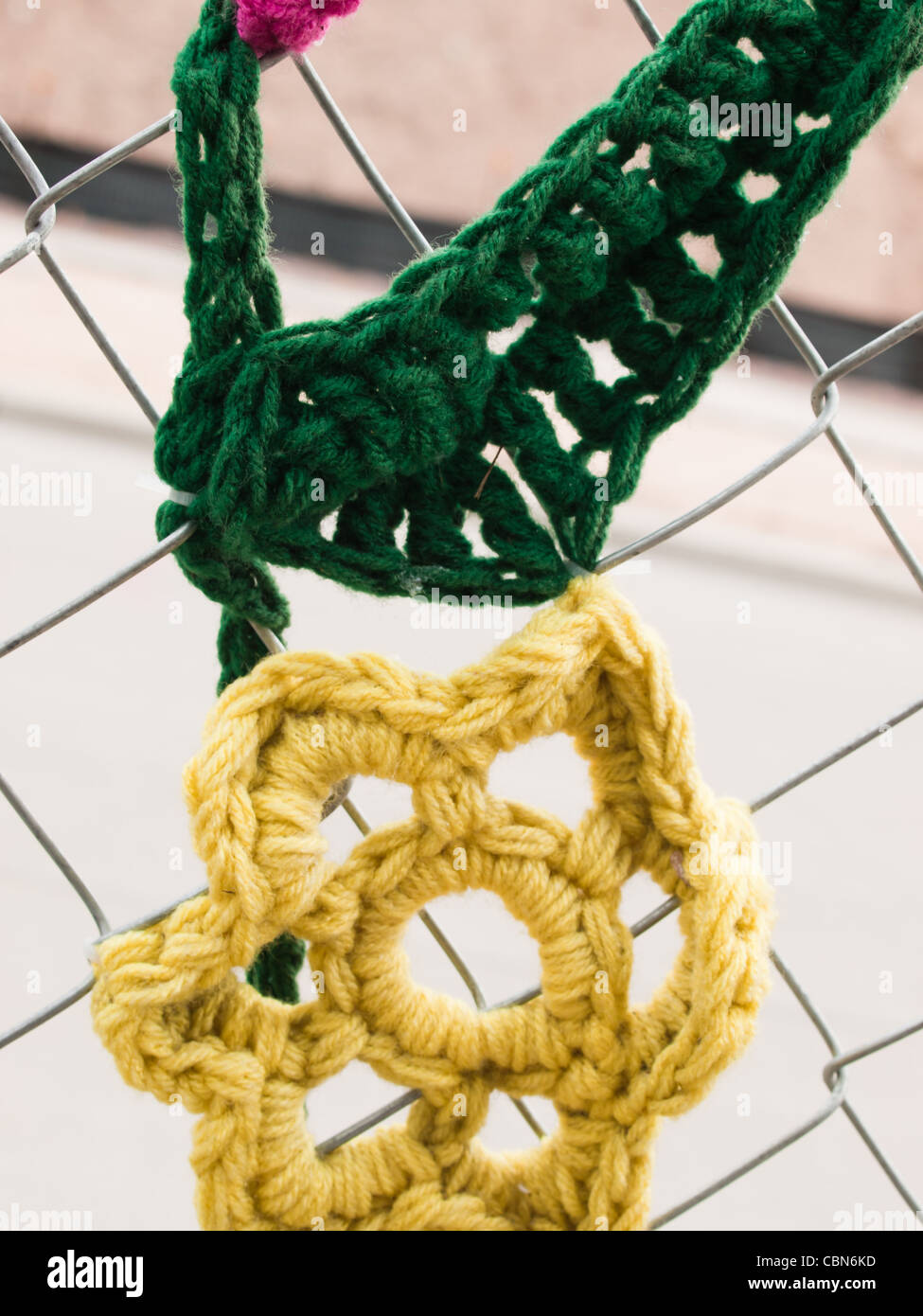 Construction fence covered with crocheted garden creatures like bugs ...