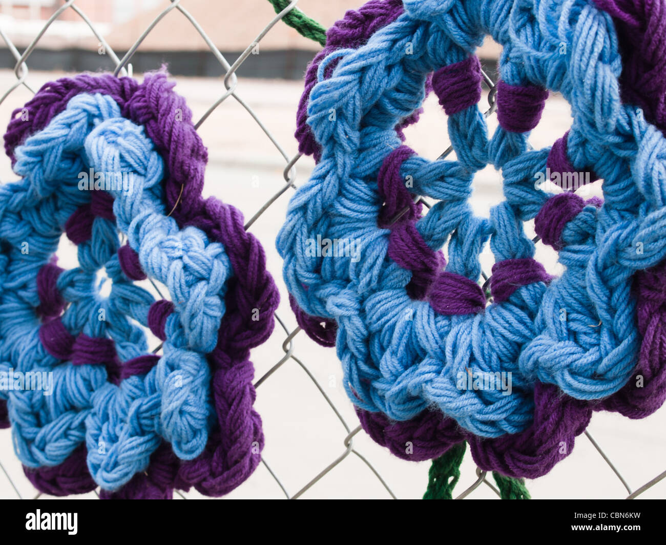 Construction fence covered with crocheted garden creatures like bugs ...