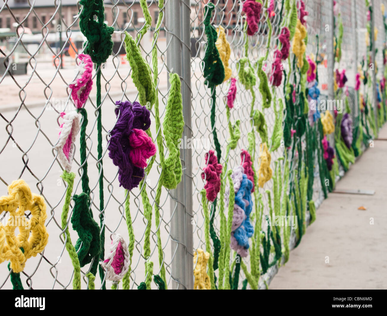 Construction fence covered with crocheted garden creatures like bugs ...