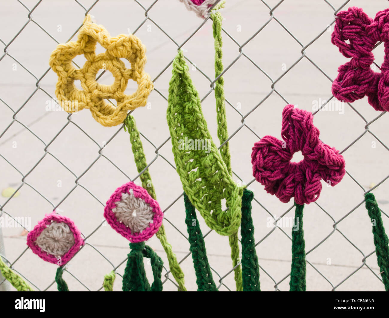 Construction fence covered with crocheted garden creatures like bugs ...