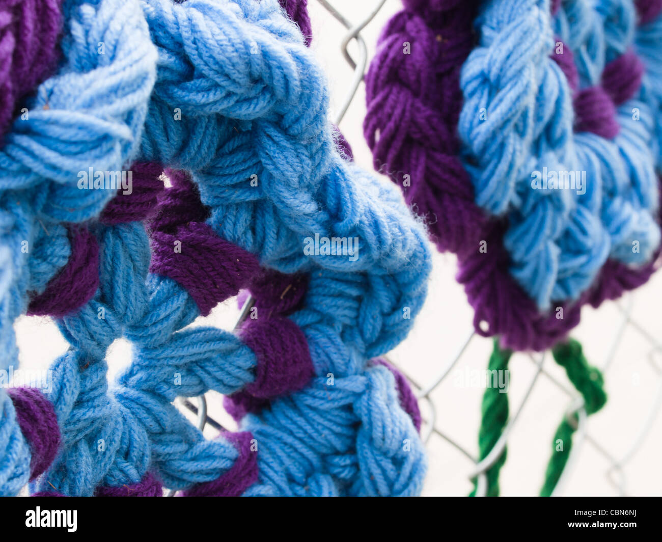 Construction fence covered with crocheted garden creatures like bugs ...