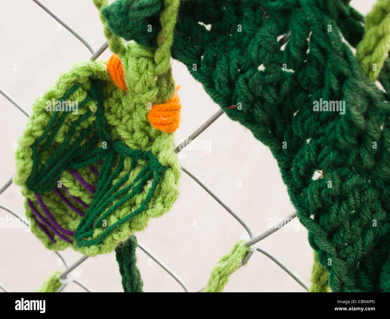 Construction fence covered with crocheted garden creatures like bugs ...