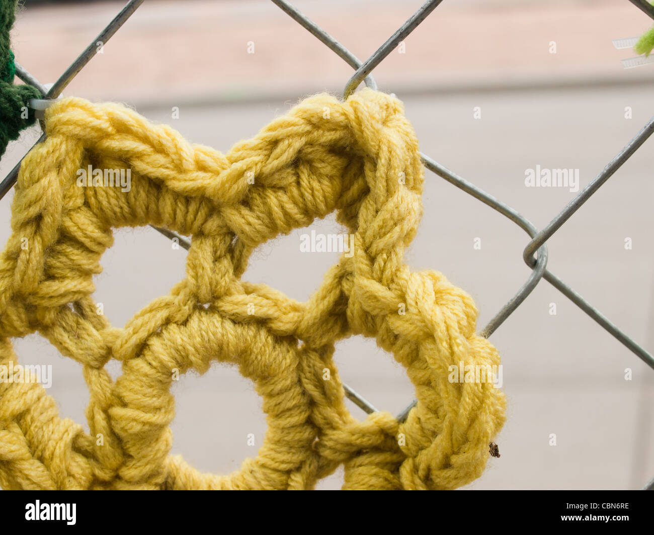 Construction fence covered with crocheted garden creatures like bugs ...