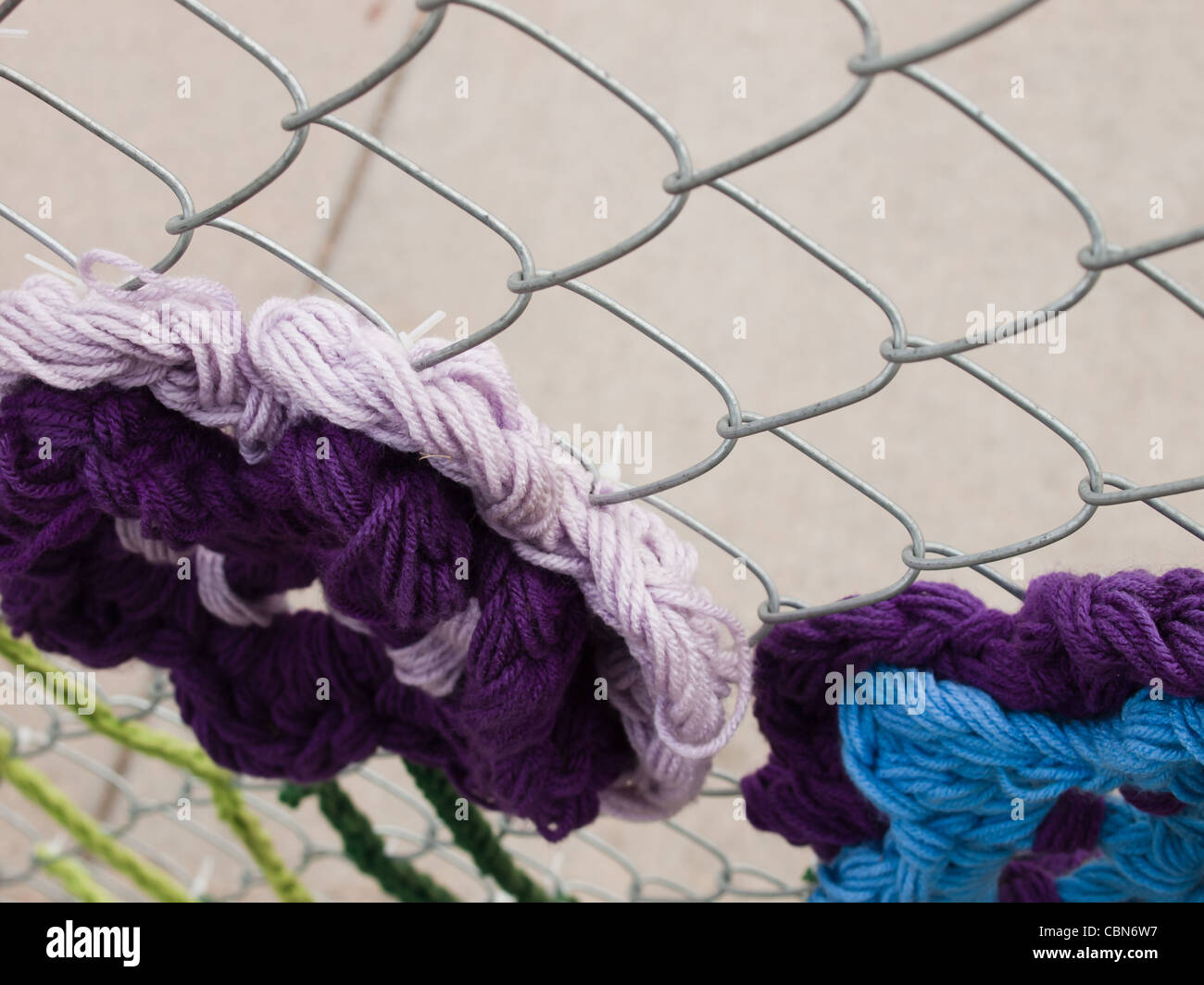 Construction fence covered with crocheted garden creatures like bugs ...