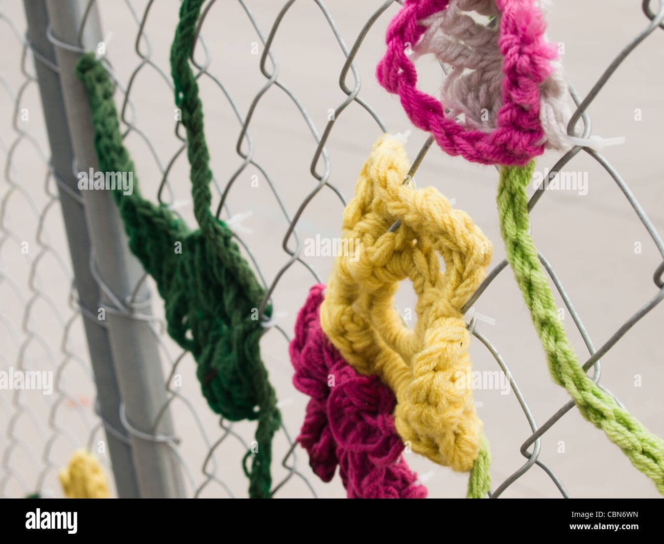 Construction fence covered with crocheted garden creatures like bugs ...