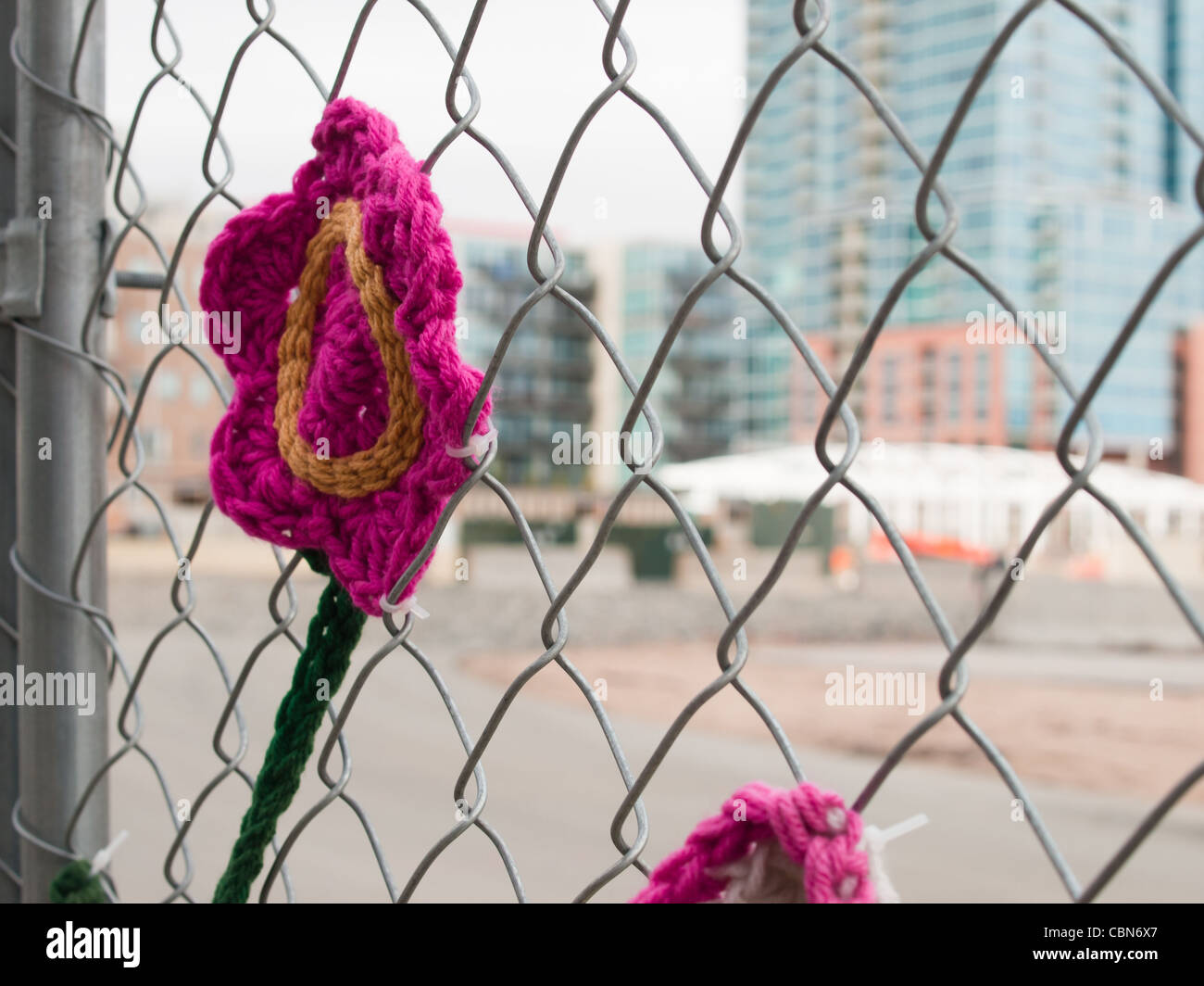 Construction fence covered with crocheted garden creatures like bugs ...
