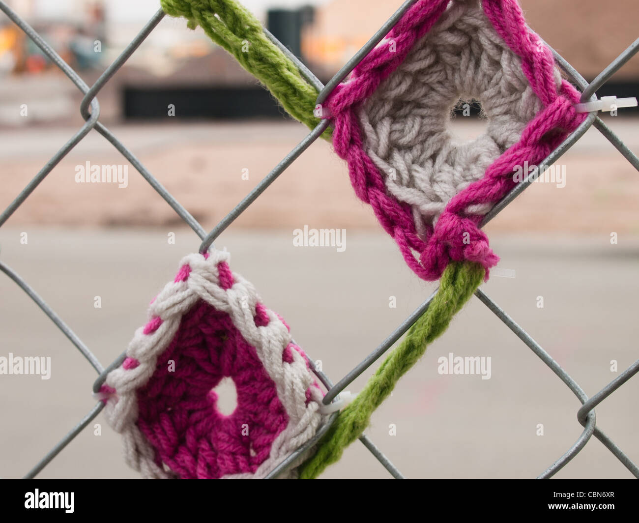 Construction fence covered with crocheted garden creatures like bugs ...