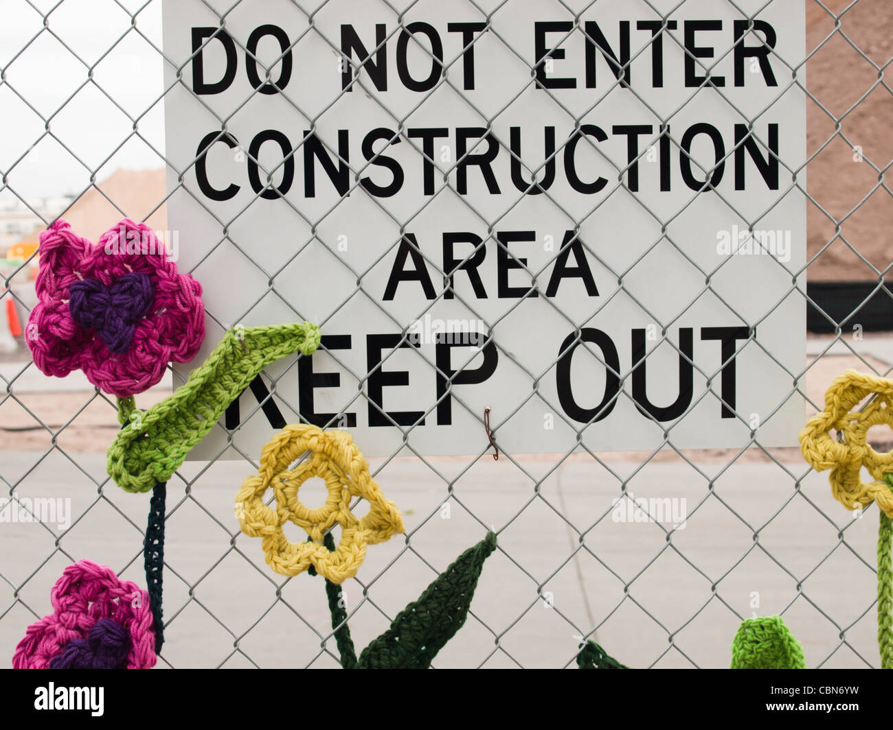 Construction fence covered with crocheted garden creatures like bugs ...