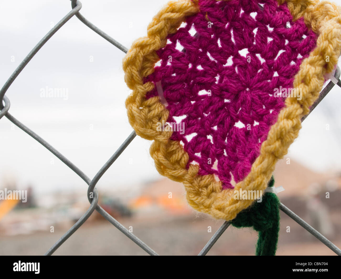 Construction fence covered with crocheted garden creatures like bugs ...