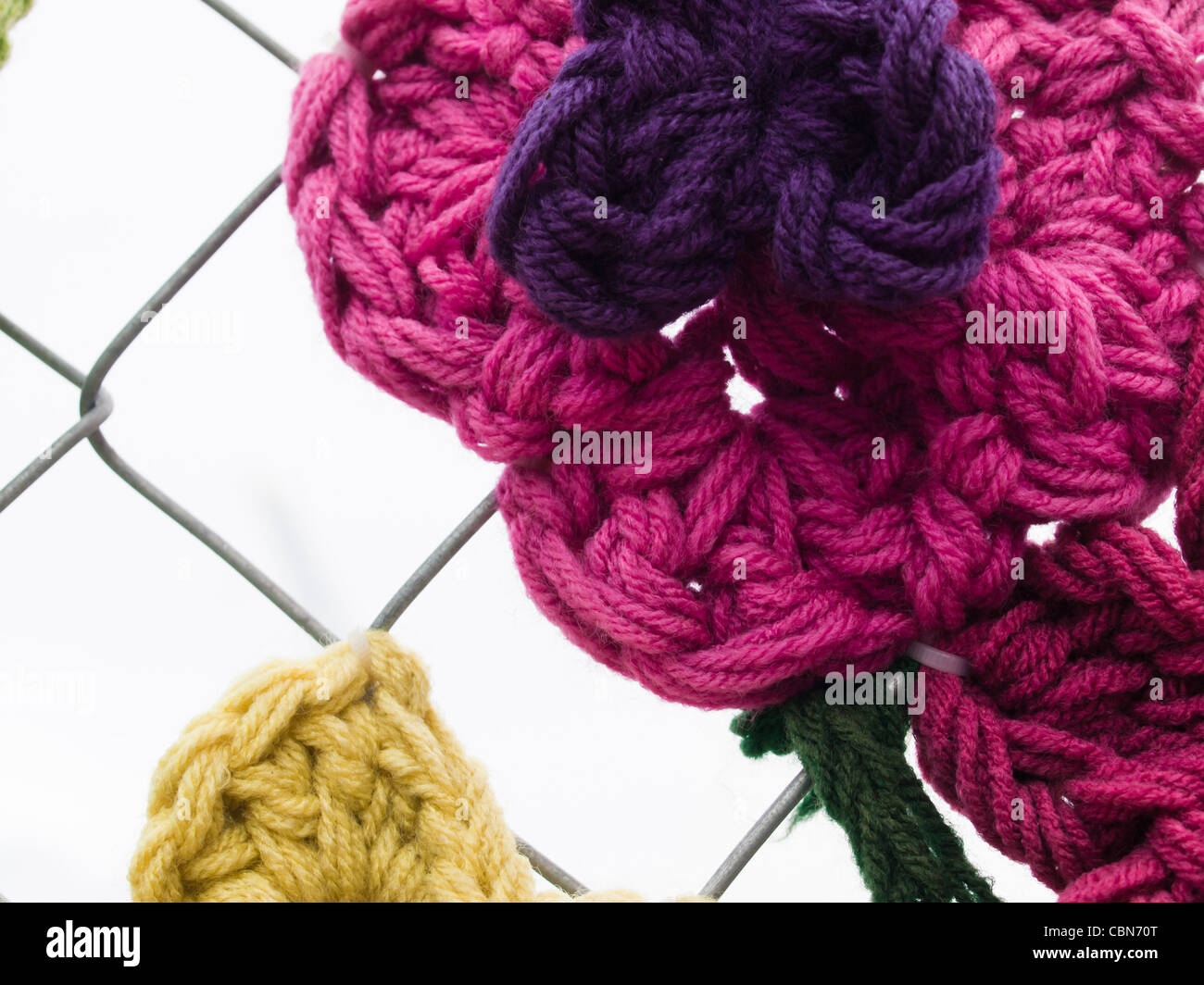 Construction fence covered with crocheted garden creatures like bugs ...
