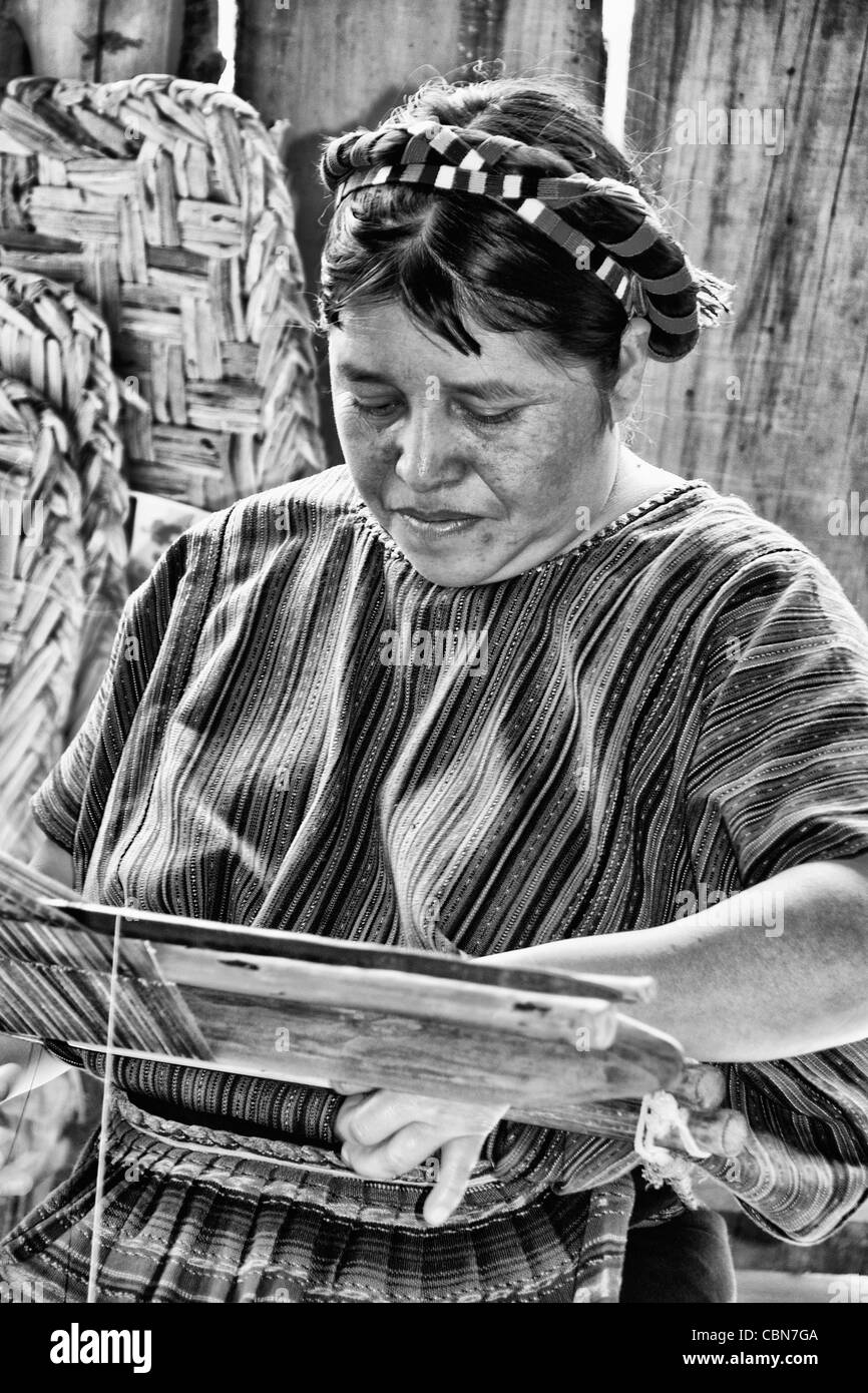 Woman at loom weaving artwork fabrics by hand in colorful dress in San ...