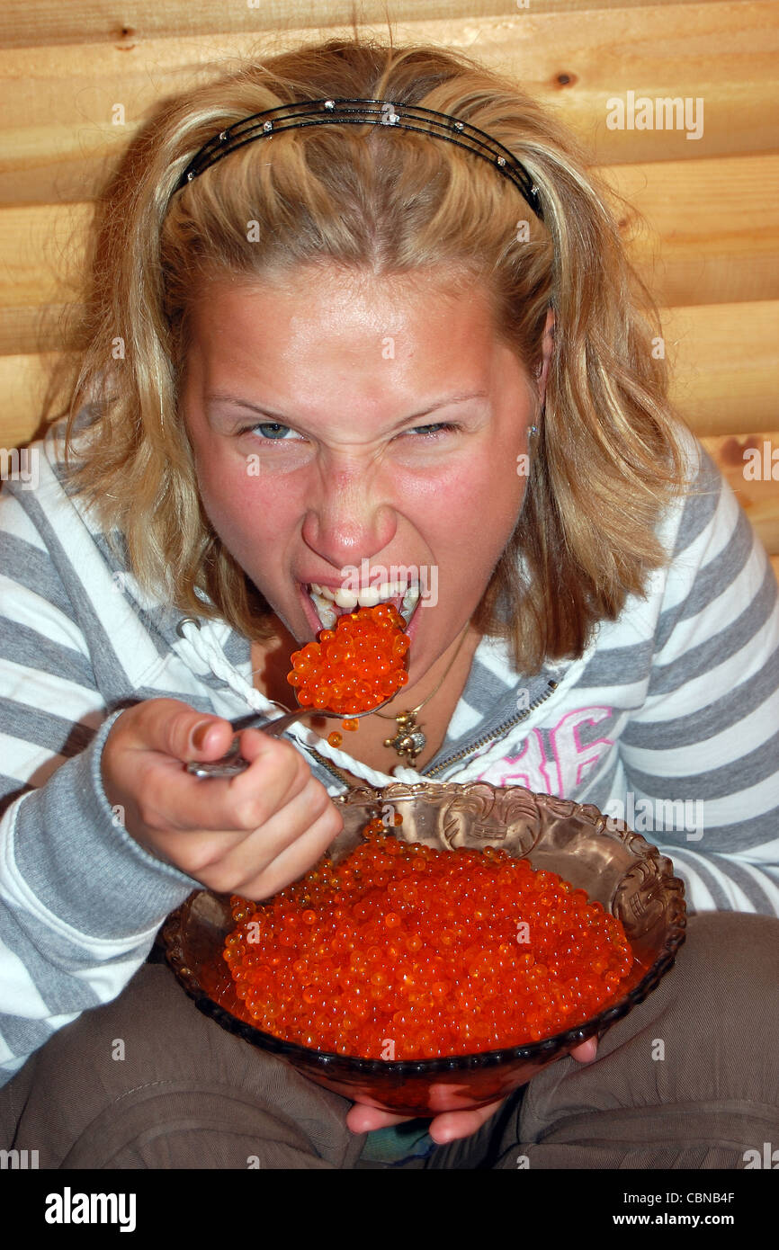 A young woman eagerly eats a caviar with red caviar Stock Photo - Alamy