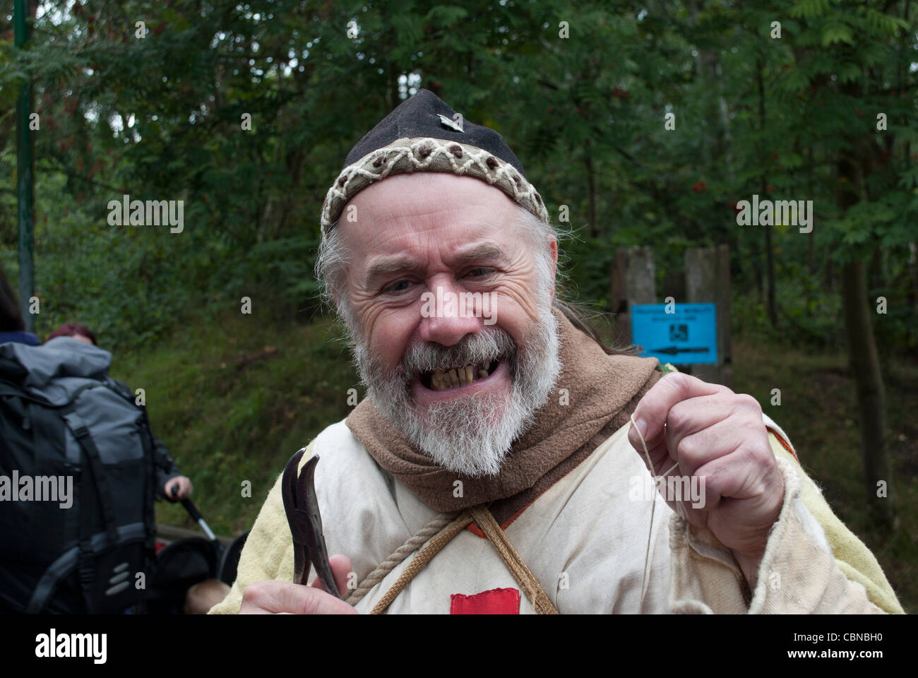 Old man in medieval costume grimacing holding up pilers and string at ...