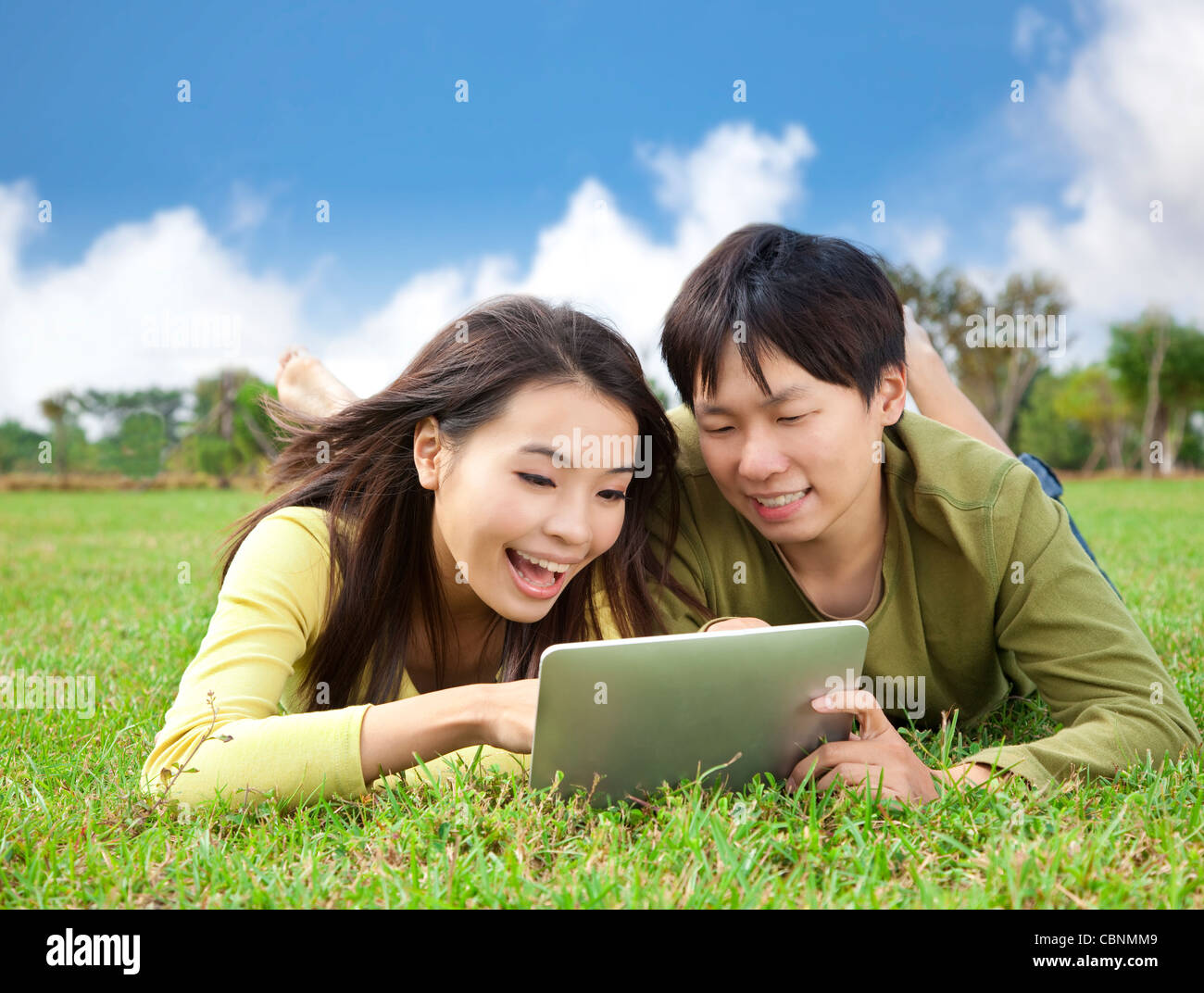 young asian student using tablet computer while lying in the park Stock ...