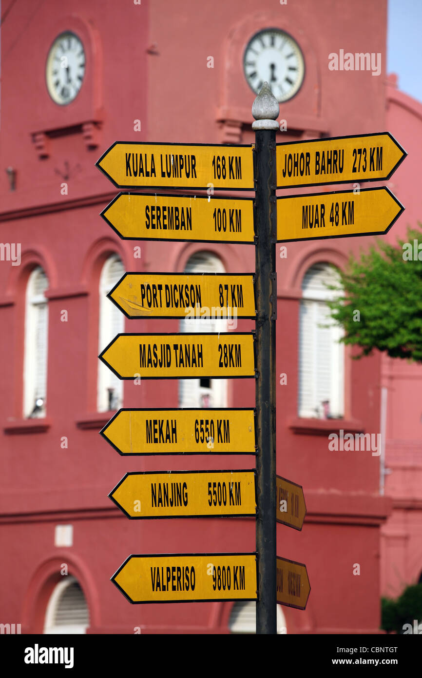 Signpost with place names and distances in front of Melaka clock tower ...