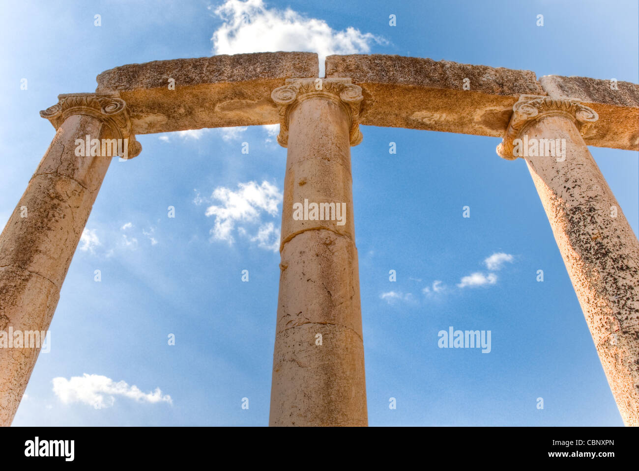 ancient roman columns against blue sky background with white clouds ...