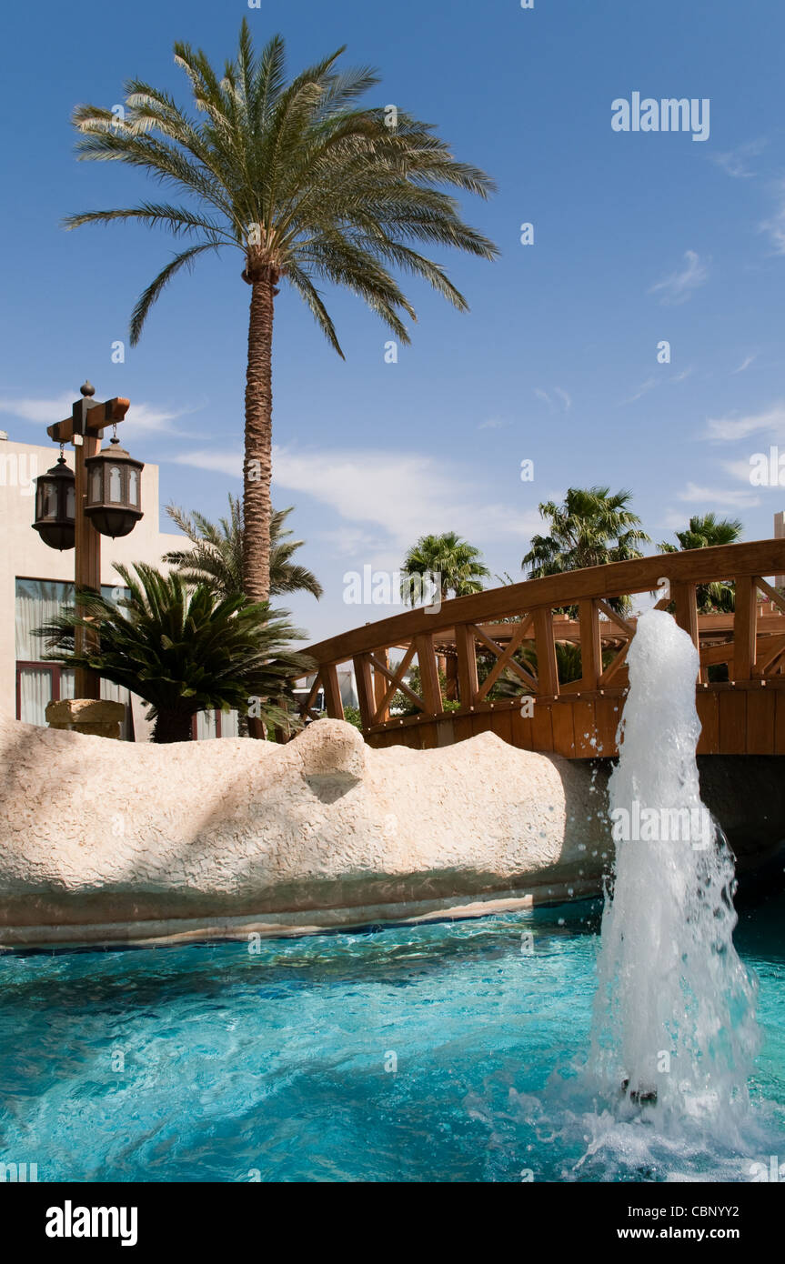 hotel pool with fountain, bridge over the pool and blue sky in ...