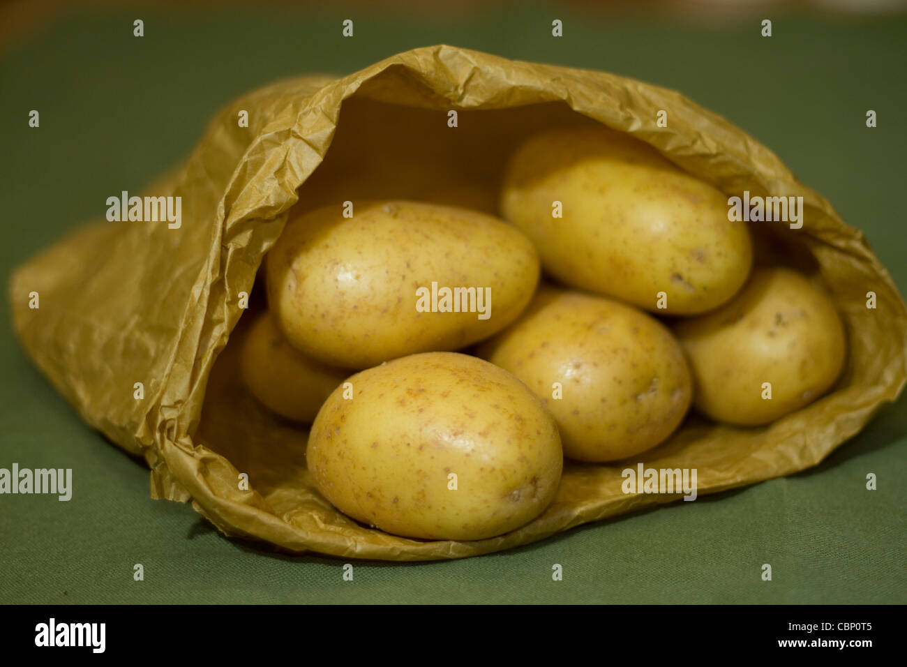 Potatoes in a brown paper bag on a rustic green background Stock Photo ...