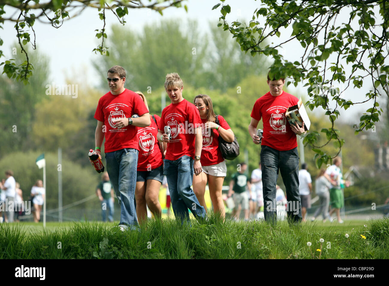 Students walking through a sports field with alcohol and drinks during ...