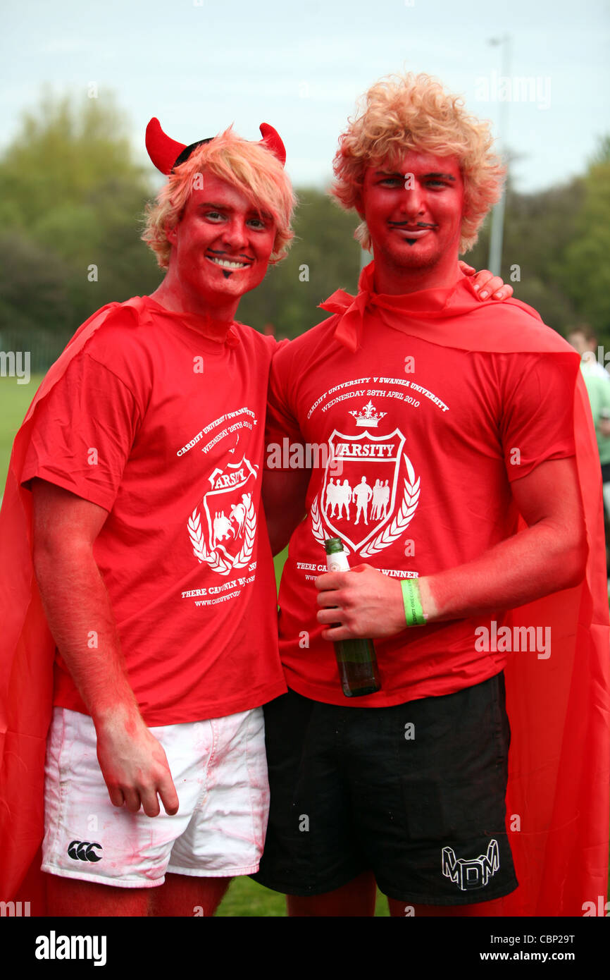 Two sports fans dressed as devils with red faces, capes and horns at a ...