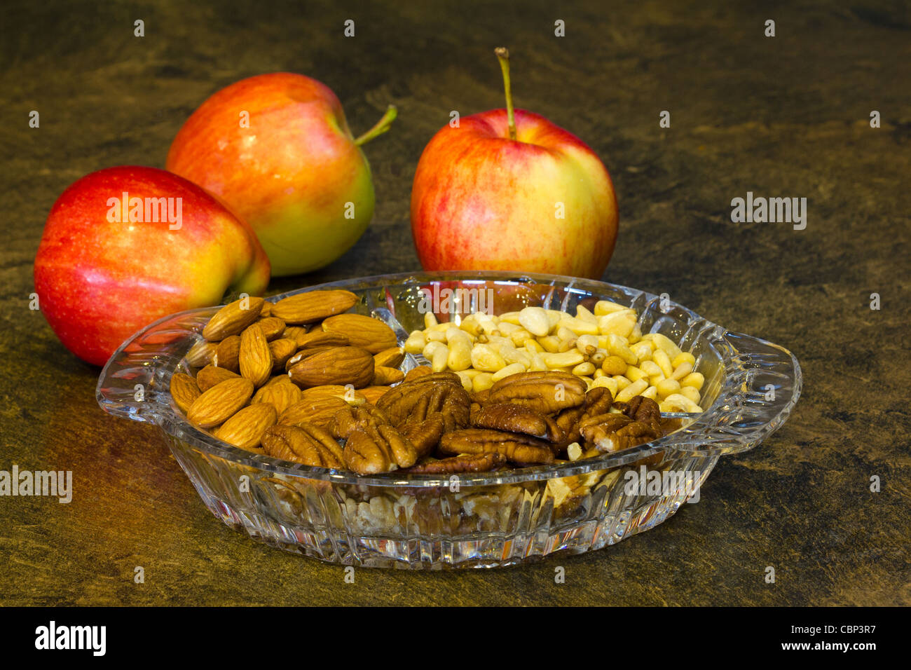 Different nuts in the crystal bowl and royal gold apples Stock Photo ...