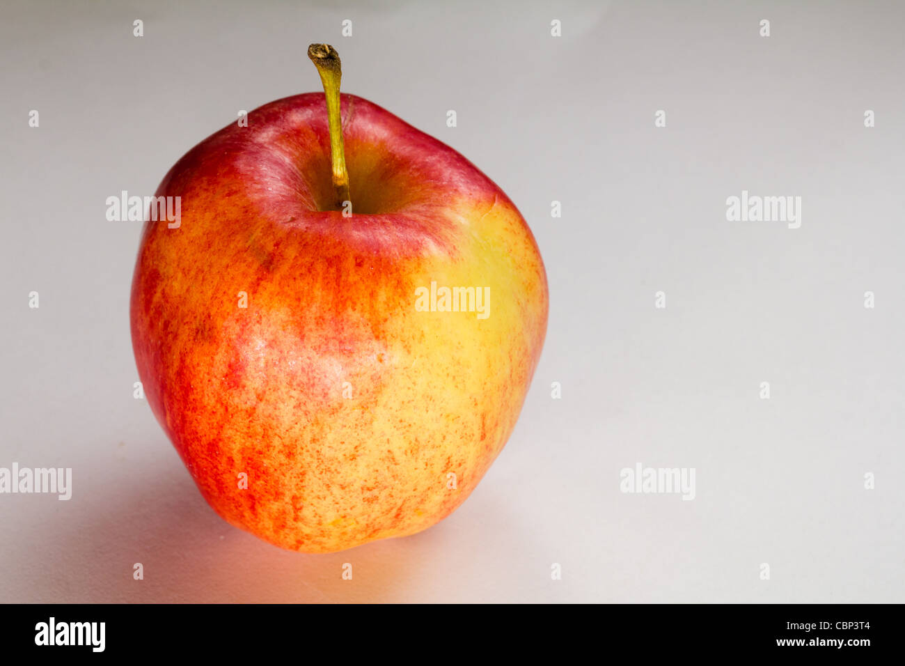 single golden red apple against a light background Stock Photo - Alamy
