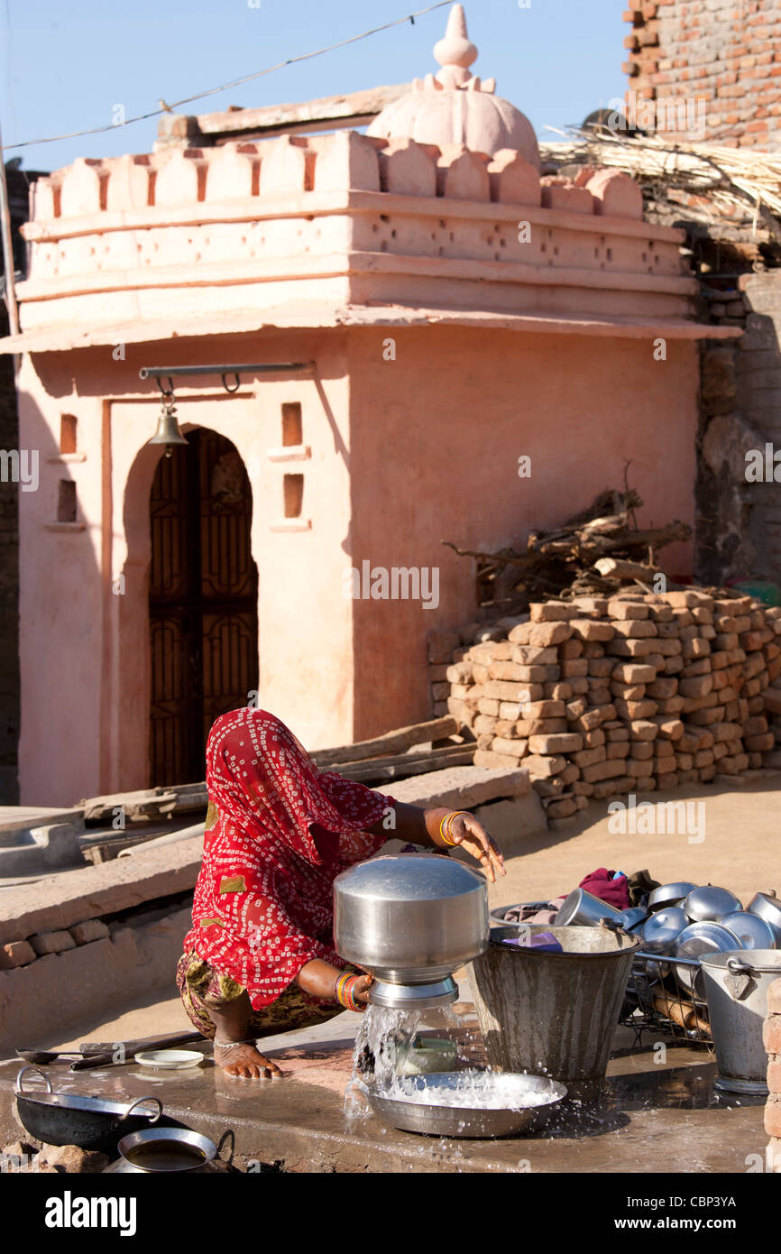 Indian woman washing pots at home in Narlai village in Rajasthan ...