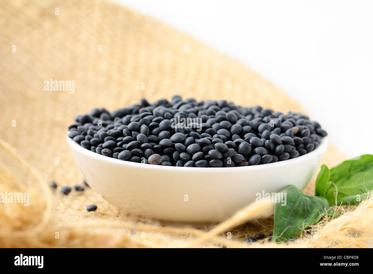 Bowl of black lentils on white background Stock Photo - Alamy