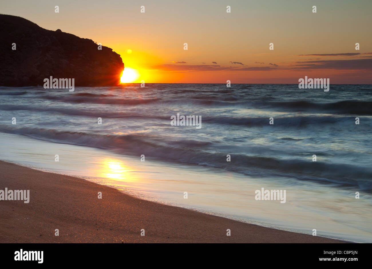 Sut setting over the sea at the beach background Stock Photo - Alamy
