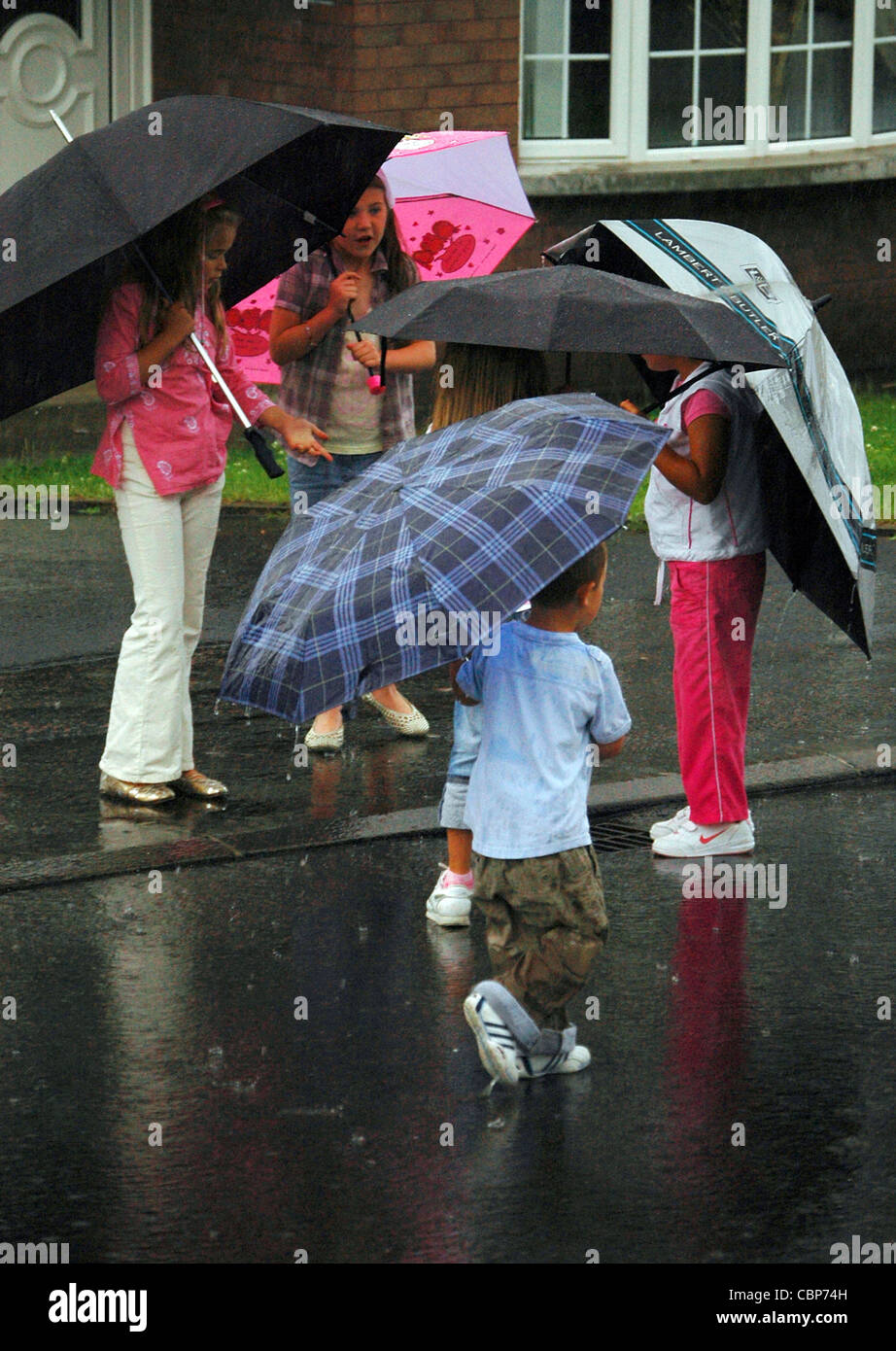 Children with umbrella standing in the rain hi-res stock photography ...