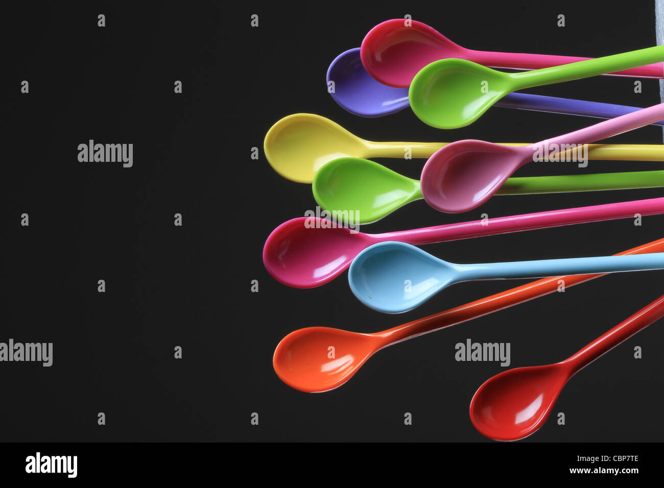 Spoons of different colors on even background Stock Photo - Alamy