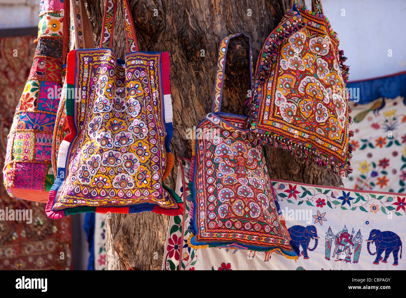 Decorated handbags on sale hanging from tree in street market in City ...