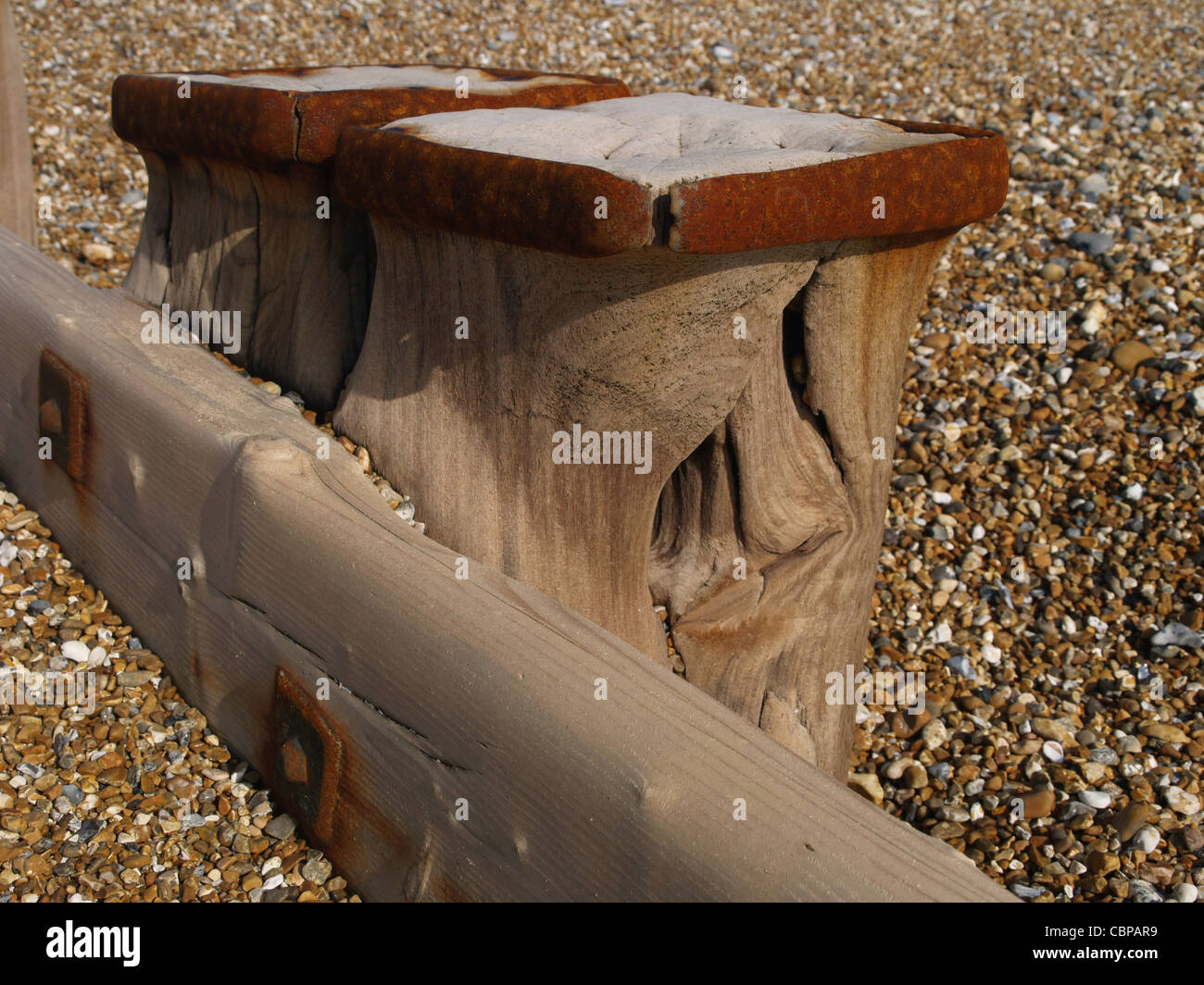 Two smooth posts of a breakwater and connecting wood on a stony beach ...