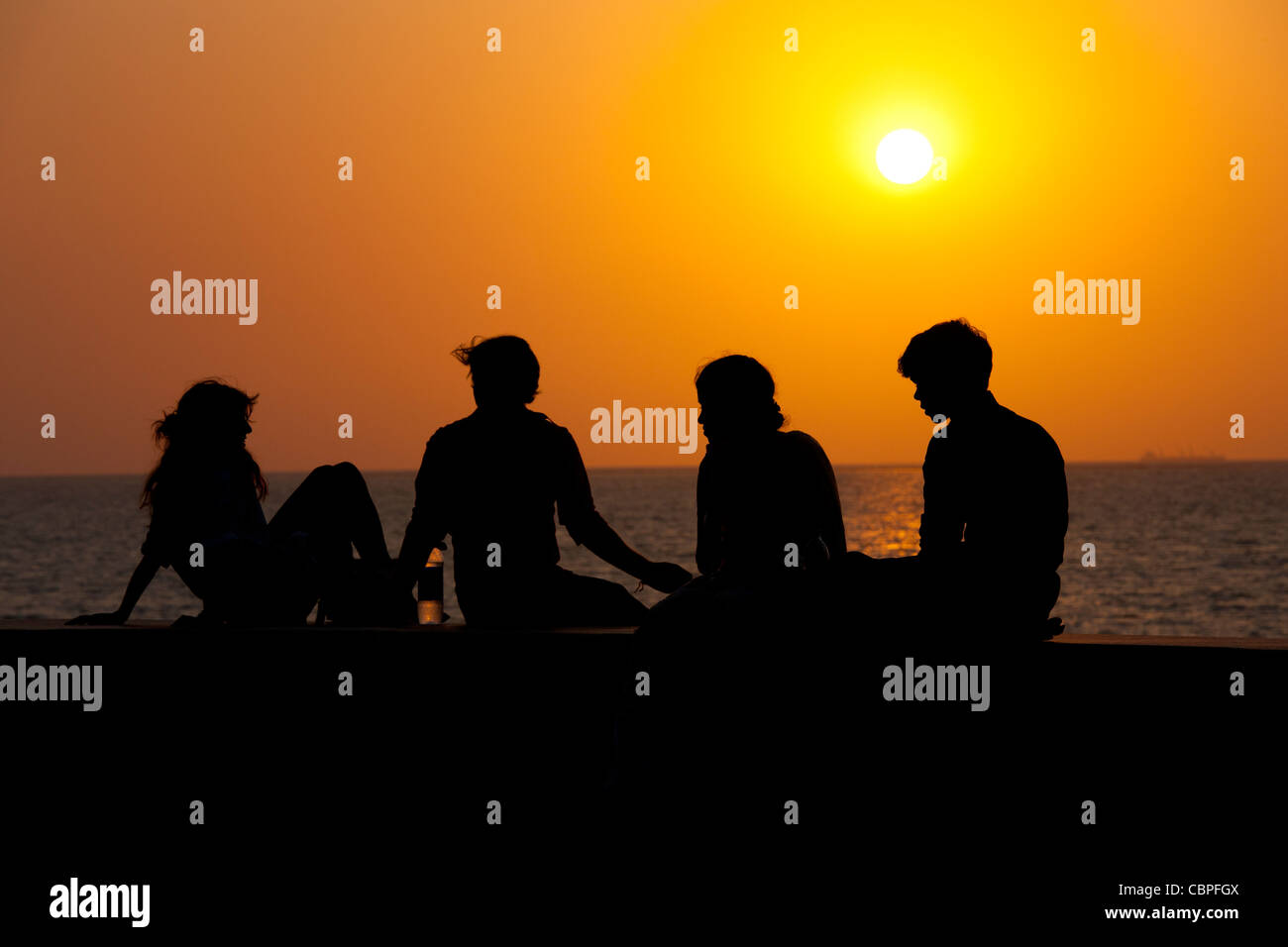 Young Indians sit on seawall at sunset at Nariman Point, Mumbai ...