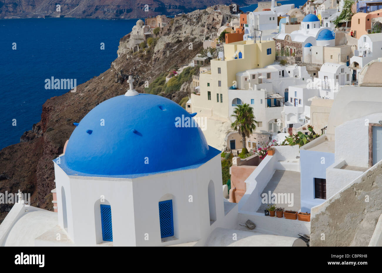 White buildings with steep slope with blue dome churches on mountain in ...