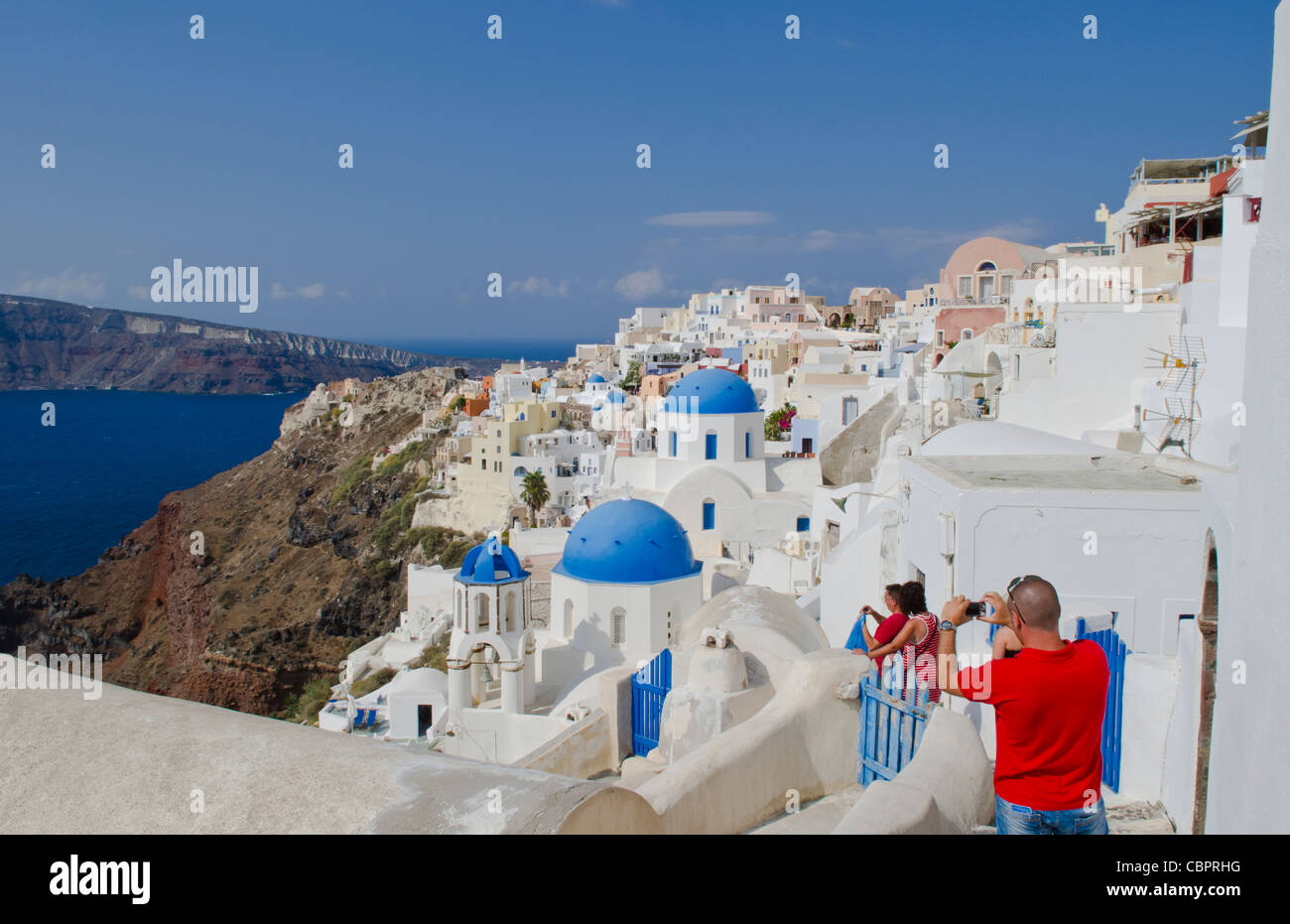 Tourist in red taking photo with white buildings with steep slope with ...