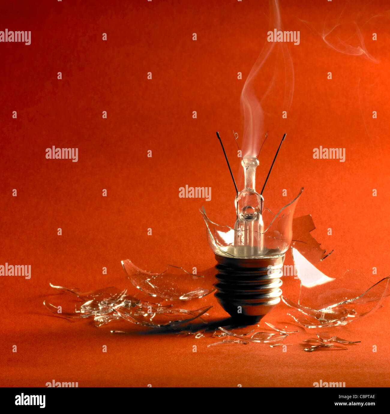 broken upright light bulb with smoke and lots of shards in orange red ...