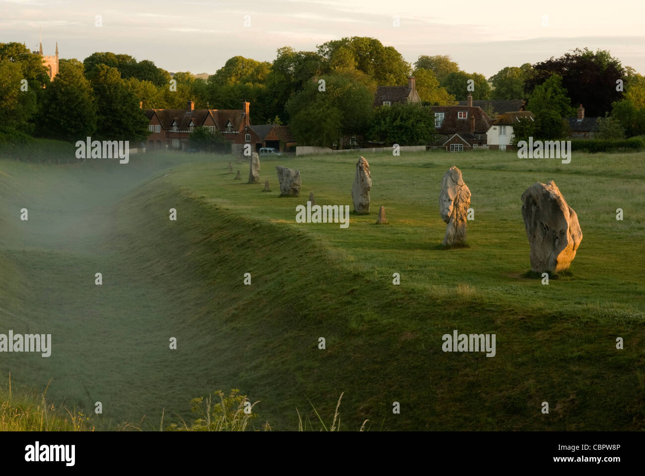 Standing stones at Avebury, England with dawn mist flowing into ditch ...