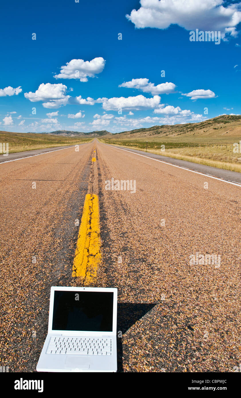 Computer in middle of remote road with Information Highway with ...