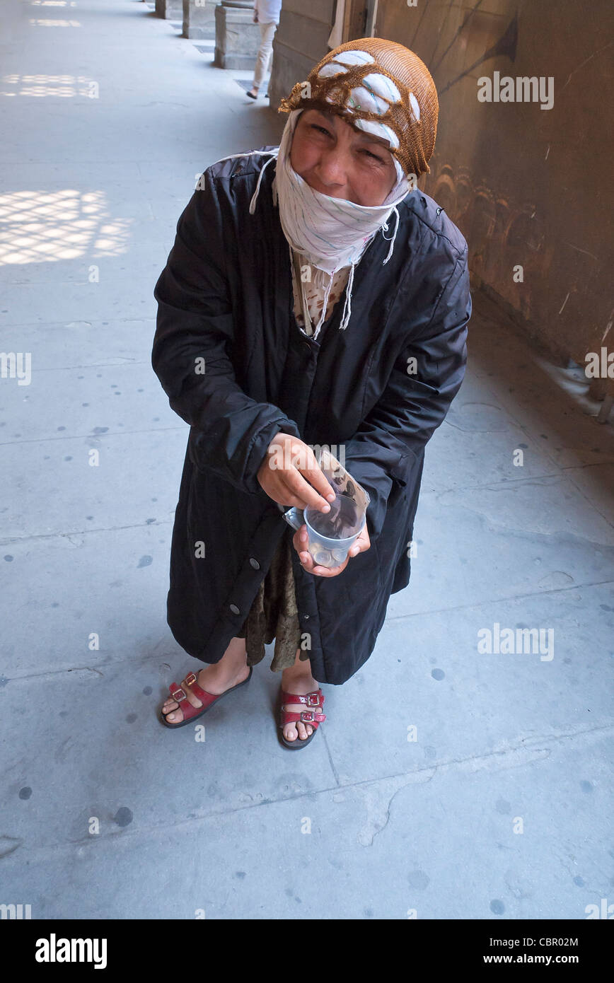 Woman beggar gestures for money while holding photograph of her ...