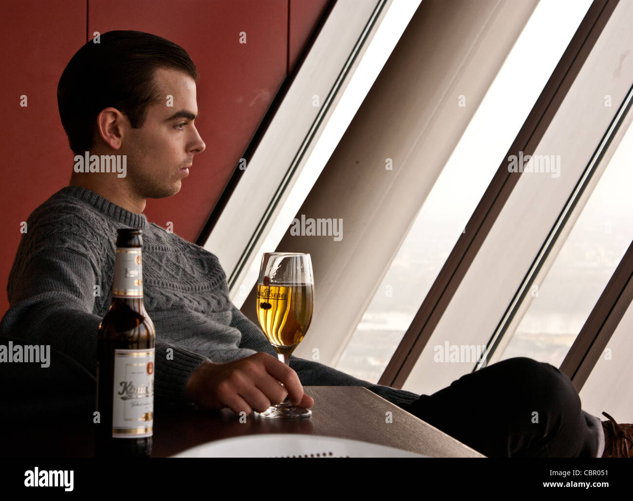 Young lone male sitting and drinking from a beer glass Stock Photo - Alamy