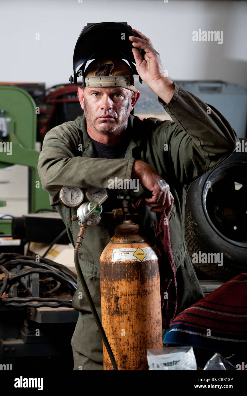 A grease covered blue collar working man takes a break, looking ...